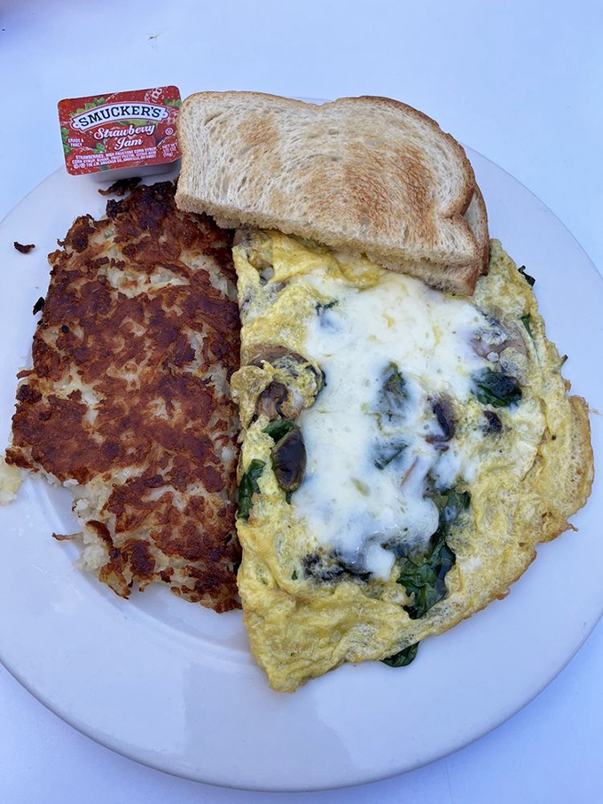 This isn't just an omelet—it's a masterclass in egg engineering, with that crispy hash brown sidekick stealing scenes like a veteran character actor.