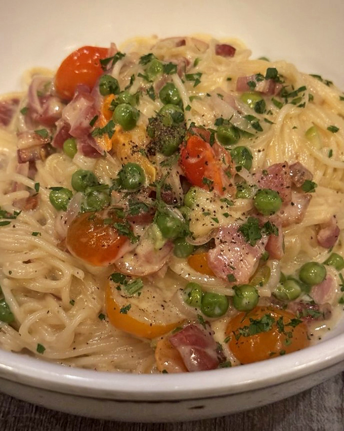 Carbonara that respects tradition while flirting with decadence. Those green peas and cherry tomatoes add pops of color to creamy perfection.