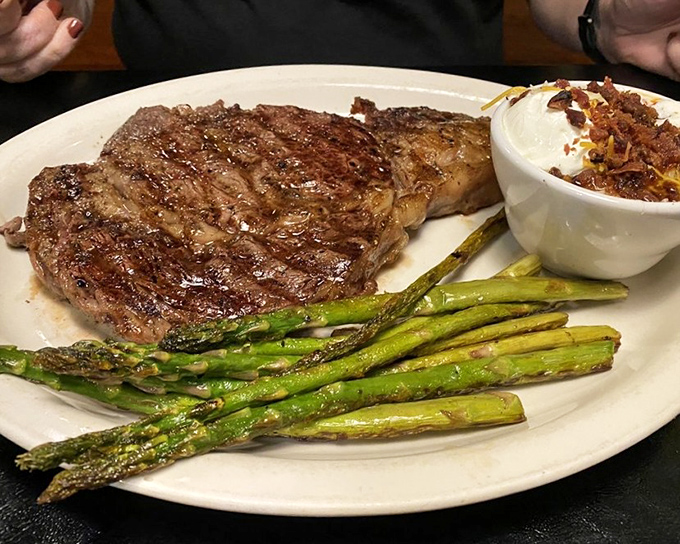A ribeye with the perfect fat-to-meat ratio sits alongside asparagus and a loaded potato&mdash;the holy trinity of steakhouse perfection.