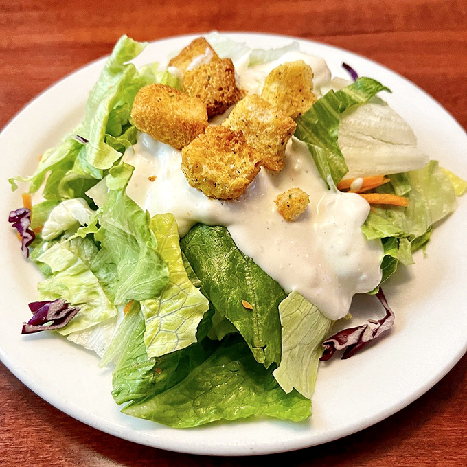 A simple house salad that knows its role&mdash;bringing crisp, fresh contrast to the richness that's coming, with croutons that crunch like they mean business.
