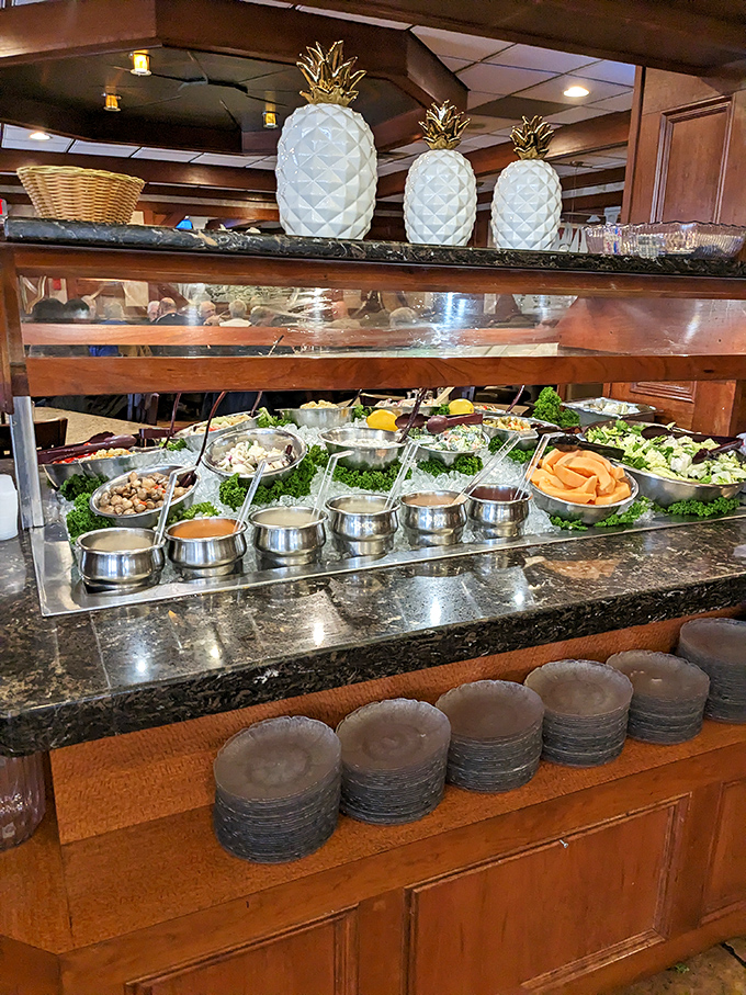 The salad bar, crowned with decorative pineapples, proves healthy options can coexist peacefully with comfort food indulgence.