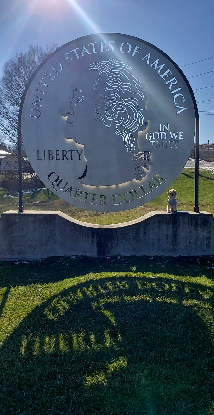 Even the smallest visitors (and their four-legged friends) look tiny next to this massive money. The quarter casts an impressive shadow across the lawn.
