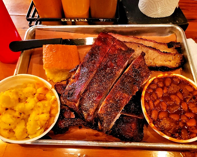 A metal tray bearing ribs, cornbread, and sides isn't just dinner&mdash;it's a love letter written in smoke and spice rub.