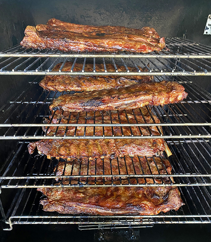 Racks on racks on racks. These ribs getting their smoke bath represent the patience that separates good BBQ from greatness.