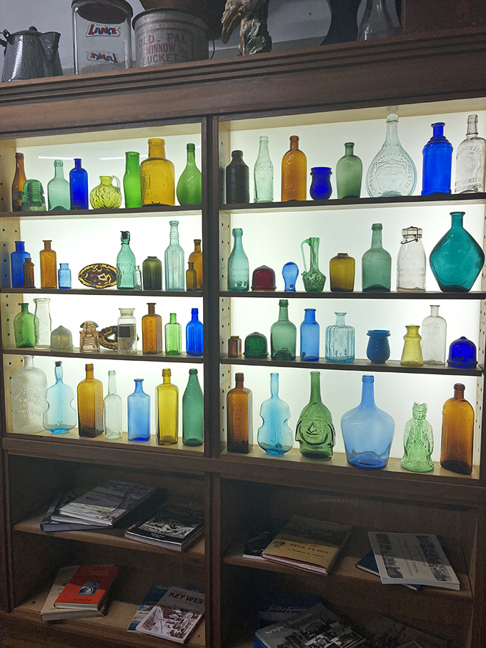 A rainbow of vintage bottles backlit like liquid jewels &ndash; proof that even empty containers can be filled with beauty.
