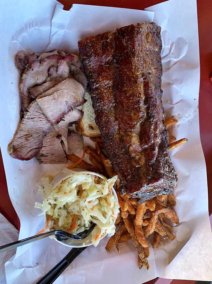 A barbecue platter that's basically a love letter written in smoke and spice. That half-eaten slaw suggests someone couldn't wait to dig in.