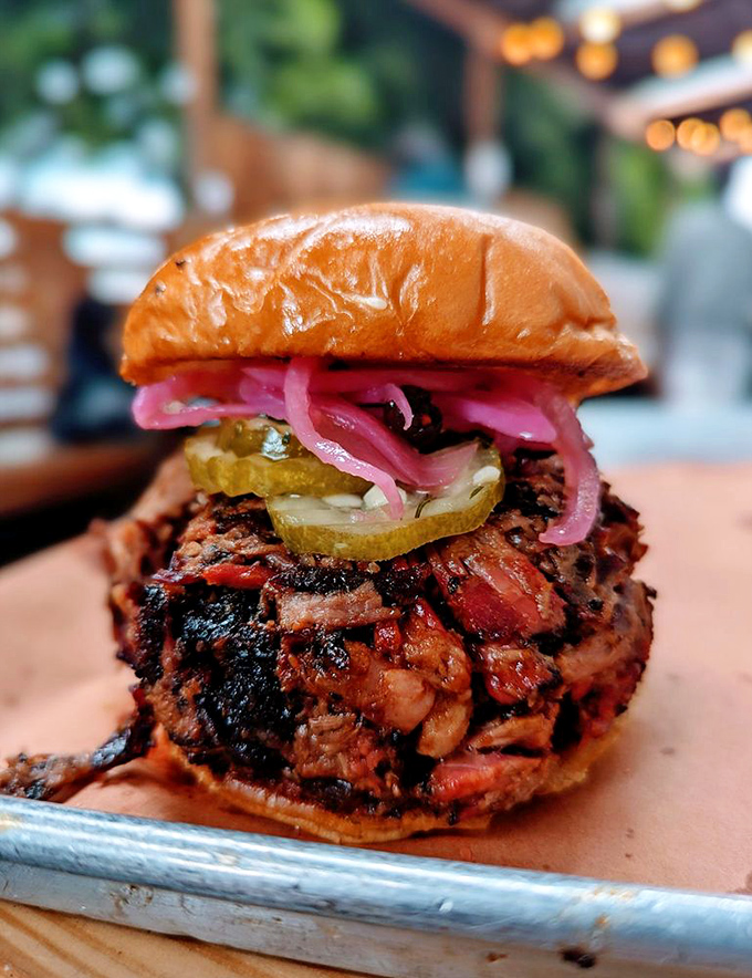 The brisket sandwich – where pickles, pink onions, and crusty-edged meat create the kind of harmony that deserves its own musical score.