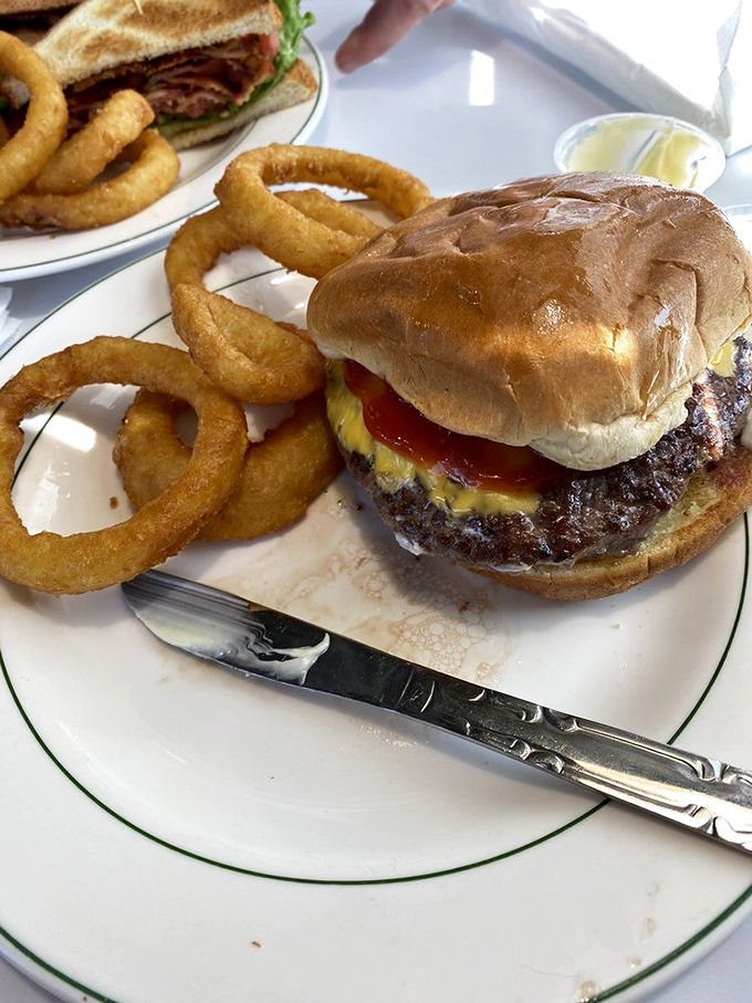 A burger that requires both hands, a stack of napkins, and possibly a nap afterward&mdash;flanked by onion rings that could double as golden bracelets.