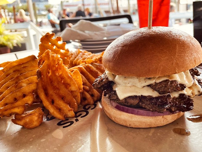 A burger that demands two hands and zero distractions. Those waffle fries aren't sidekicks—they're co-stars in this handheld drama of deliciousness.