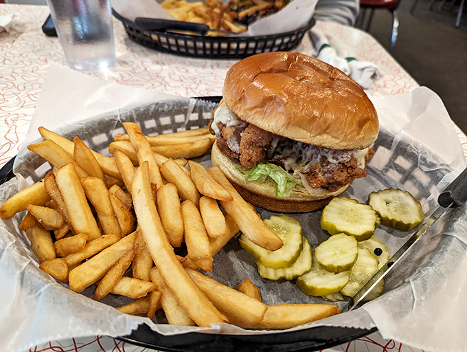 A sandwich that demands to be photographed before eaten. The golden bun, crispy fries, and pickle chips create the holy trinity of lunch perfection.
