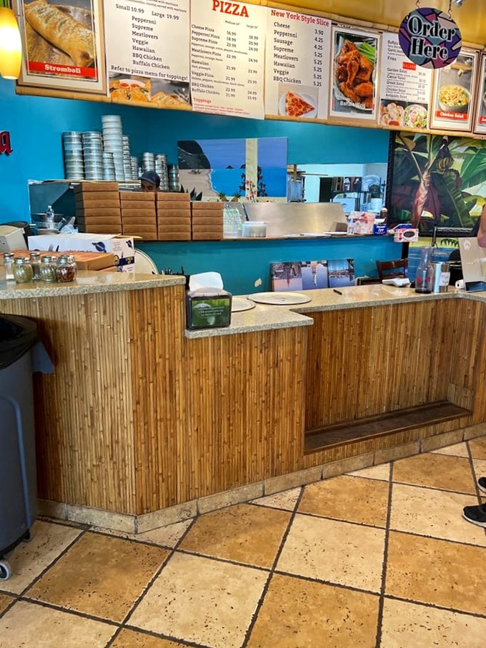 The bamboo-fronted counter where pizza dreams come true. Behind this humble barricade, magic happens daily in the form of dough and cheese.