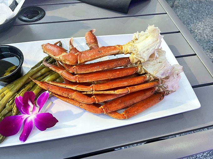 Snow crab legs arranged like nature's perfect architecture. The purple orchid isn't just garnish&mdash;it's a reminder you're dining somewhere special.