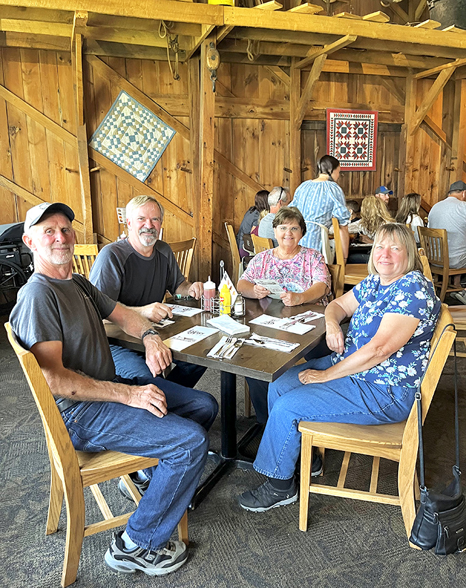 Four happy diners proving that the best conversations happen around wooden tables under barn beams with good food as the silent fifth guest.