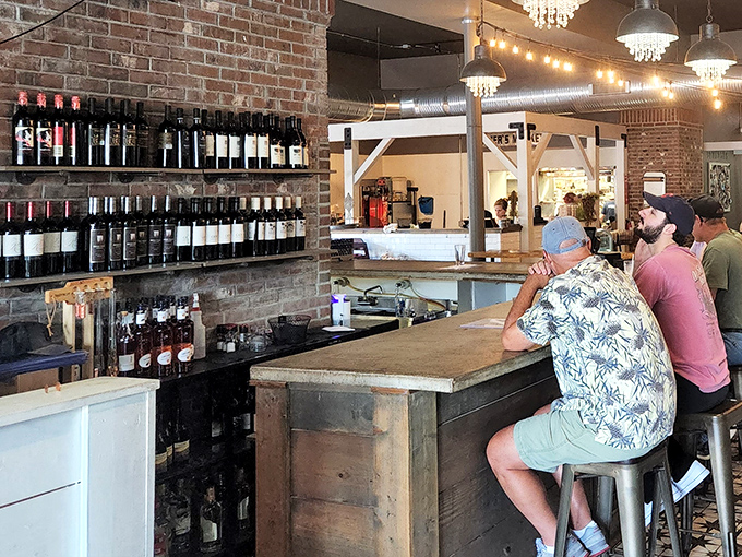 The bar area showcases an impressive wine selection against exposed brick, while patrons prove that Hawaiian shirts and good taste go hand in hand.