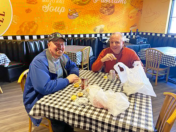 Two happy customers enjoying what appears to be the aftermath of a delicious deli raid. The smiles say it all.