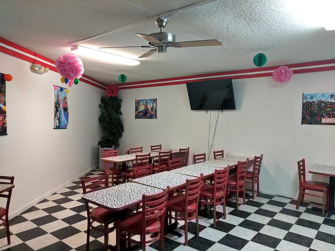 The indoor dining area's red chairs and checkered tables create a retro diner vibe that makes waiting for your burger feel like a scene from your favorite movie.
