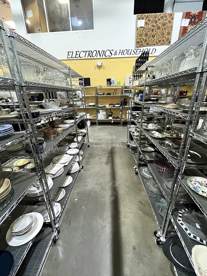 Dish paradise! Plates, bowls, and serving pieces line metal shelves like a ceramic library waiting to host your next dinner party.