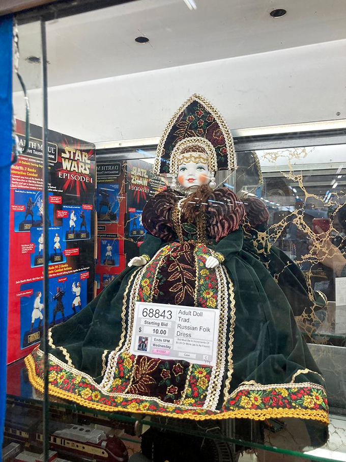 The doll in traditional Russian folk dress waits patiently behind glass for a collector who appreciates cultural craftsmanship and old-world charm.