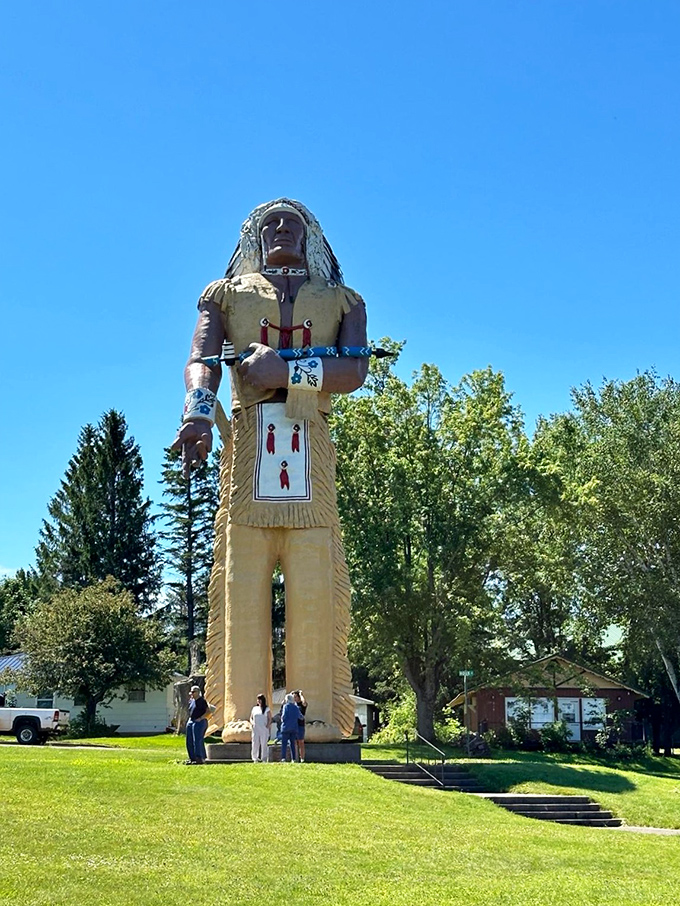 Size matters! These visitors provide perfect scale, looking like miniature figurines next to Hiawatha's towering presence.