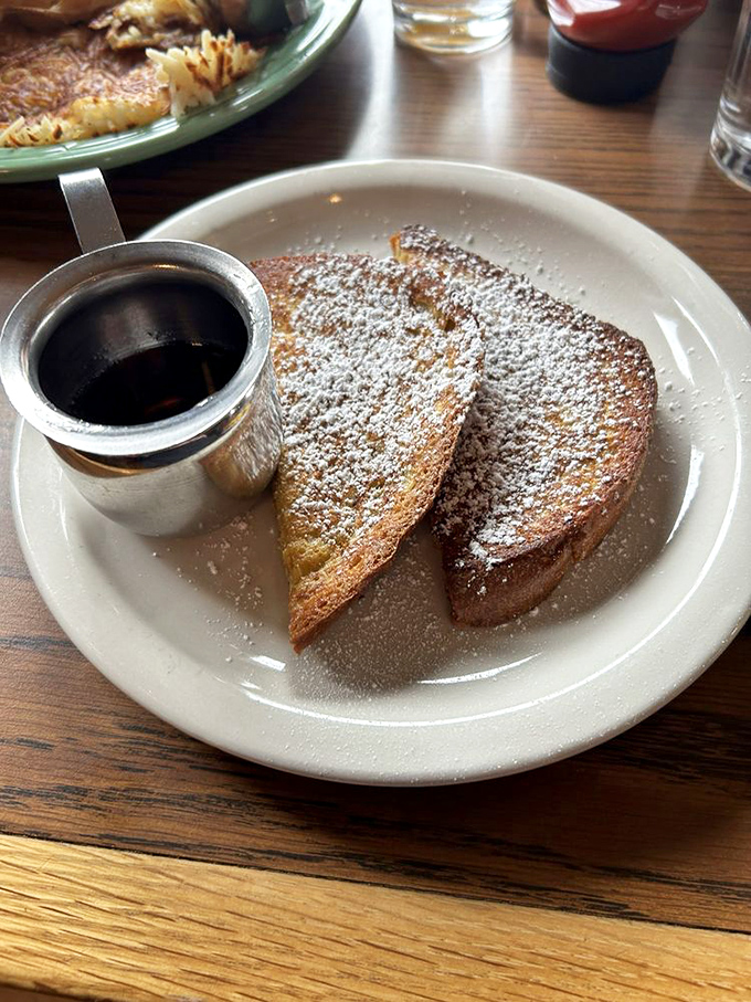 French toast dusted with powdered sugar like fresh snow, with maple syrup waiting to create a delicious avalanche of flavor.