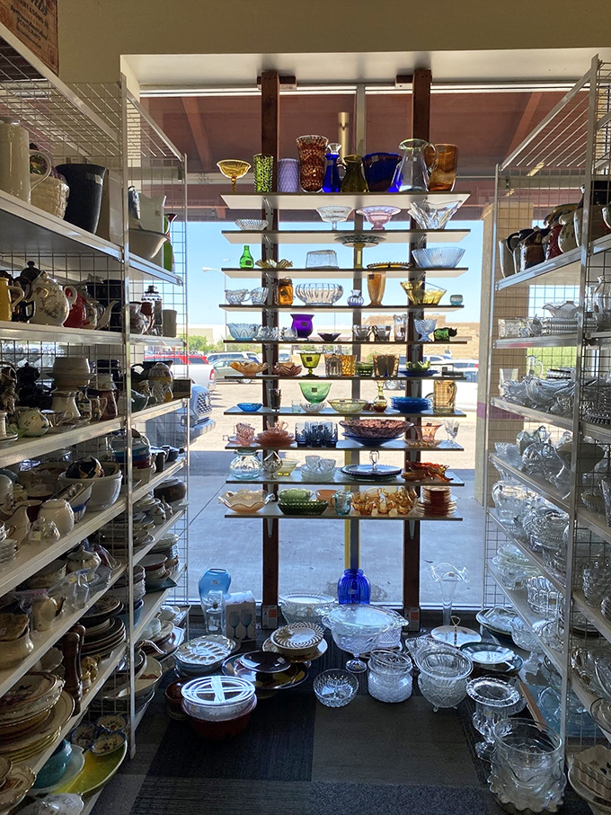 The glassware section glows with colored treasures from every era. Sunlight streams through this rainbow of Depression glass, creating a stained-glass effect worthy of a cathedral.