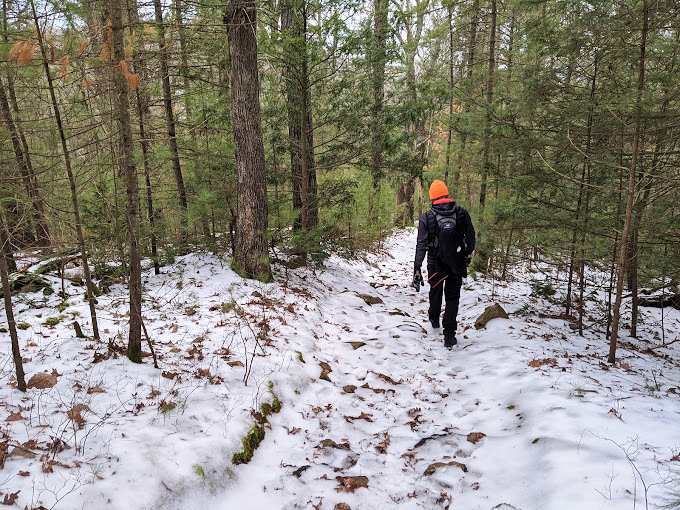 Winter hiking: where your breath becomes visible art and your toes question your life choices. The orange hat says "Don't shoot, I'm enjoying nature!"