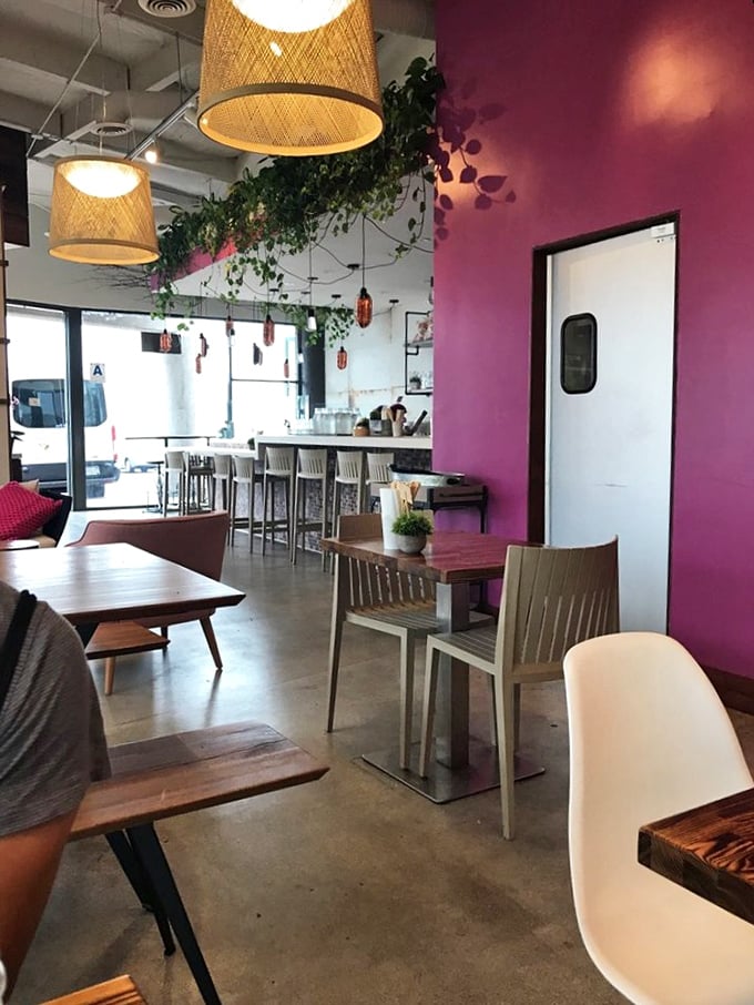 The dining room's vibrant purple wall and hanging plants create an urban oasis. It's like eating in a design magazine spread that actually serves delicious food.