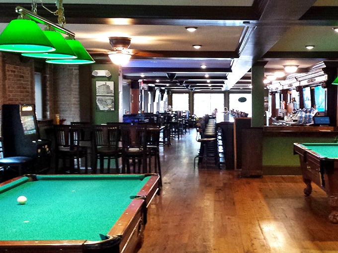 Classic green billiard lamps illuminate tables where good times roll as smoothly as the perfectly racked balls below.