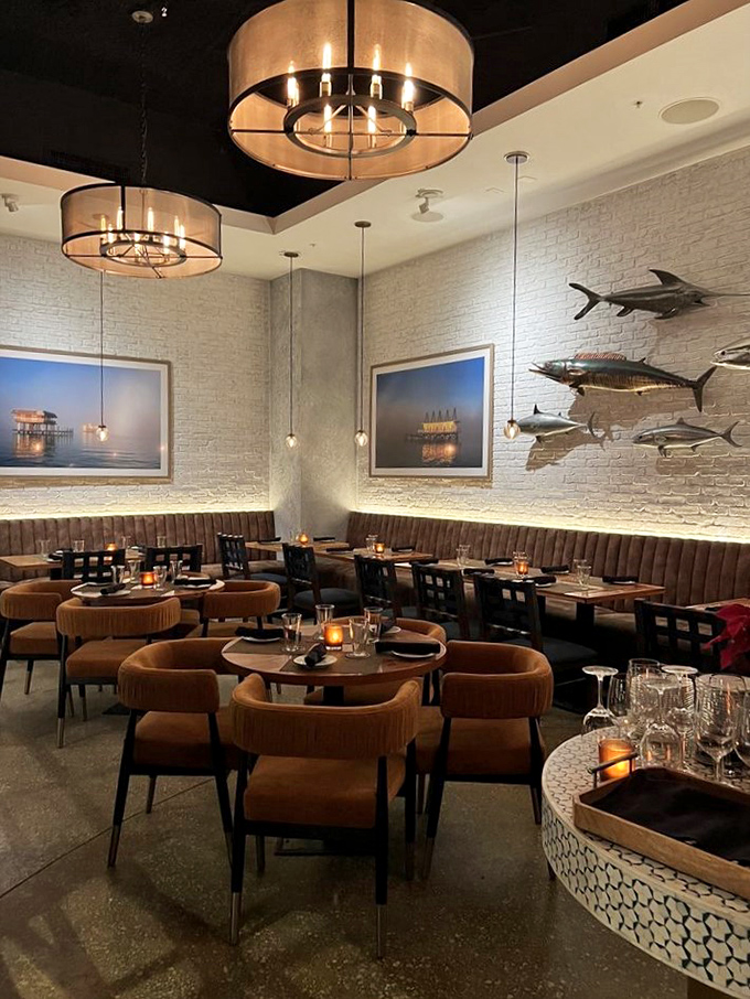 Fish sculptures swim along white brick walls while drum pendant lights cast a glow that makes everyone look like they're on vacation.