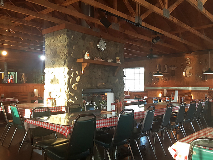 The stone fireplace anchors the dining room like a rustic cathedral to smoked meat, where checkered tablecloths serve as the stained glass.