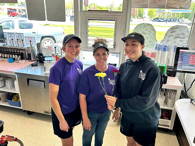 The smiling staff&mdash;guardians of comfort food traditions&mdash;holding a flower that symbolizes the blossoming joy they serve daily.