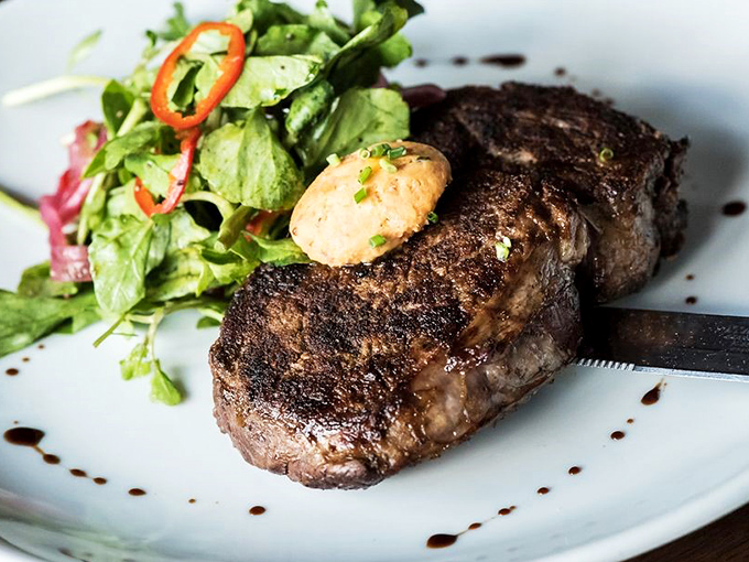 A perfectly seared steak with compound butter slowly melting into meat paradise&mdash;the kind of simple luxury that makes you forget you're technically eating on a boat.
