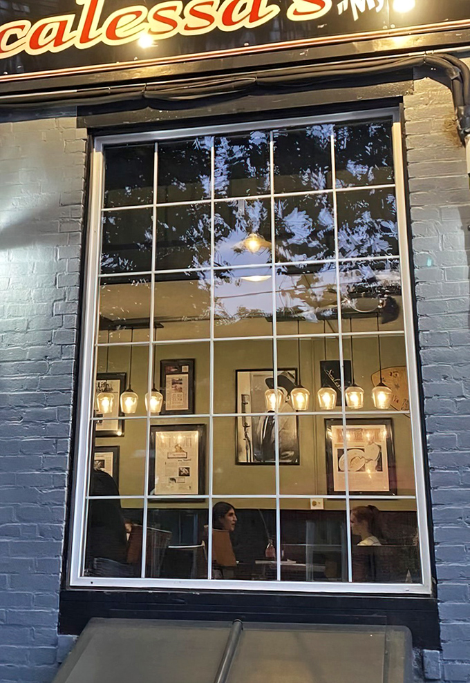 Through the window, pendant lights glow like fireflies, inviting passersby to step into this cozy Italian time capsule on a Wilmington evening.
