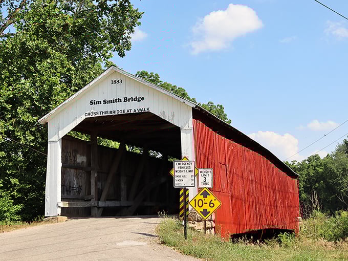 The Sim Smith covered bridge wears its red paint like a badge of honor, standing as a wooden time capsule from 1883 that still carries travelers today.