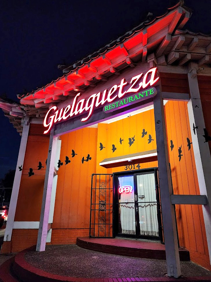 Guelaguetza's vibrant orange facade and flying bird silhouettes hint at the colorful Oaxacan experience waiting inside.