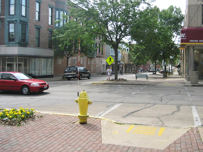 The yellow fire hydrant stands guard on Freeport's brick-paved corner, a cheerful sentinel watching over streets where nobody's in a particular hurry.