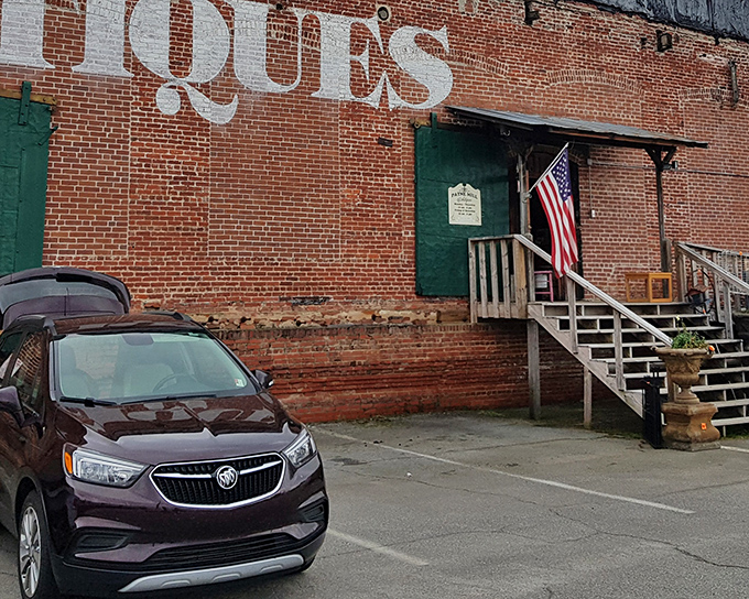 The brick exterior of Payne Mill Village Antique Mall stands like a time capsule waiting to be opened, complete with those magnificent green doors that practically whisper "treasures inside."