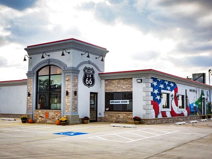 The iconic Route 66 shield beckons hungry travelers like a lighthouse for the famished. This white stone exterior with patriotic murals promises authentic Americana inside.