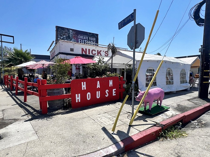 The iconic red-trimmed exterior of Nick's Café stands like a beacon of breakfast hope in downtown LA, complete with cheerful striped umbrellas and that unmistakable retro charm.