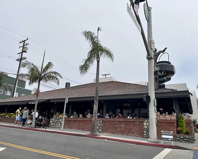 The iconic sloped roof and palm trees of The Kettle stand sentinel at Manhattan Beach's busiest corner, beckoning hungry souls like a culinary lighthouse.