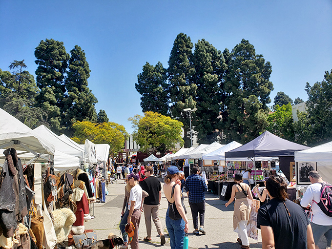White tents line the sun-drenched pathways of Melrose Trading Post, where treasure hunters navigate through a sea of vintage finds under California's perfect blue sky.