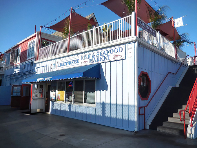 The classic coastal charm of Lighthouse Oyster Bar & Grill welcomes seafood lovers with its distinctive blue and white exterior, promising maritime delights within.