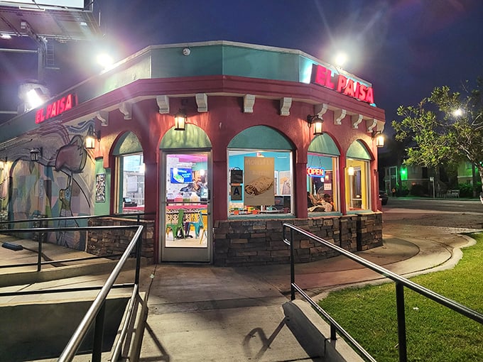 The coral-colored exterior of Tacos El Paisa glows like a beacon in the night, promising authentic Mexican flavors to all who approach.