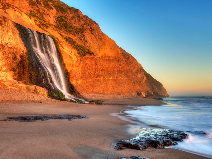 Nature's perfect sunset backdrop – Alamere Falls cascades 40 feet directly onto the beach, creating California's most dramatic meeting of fresh and salt water.