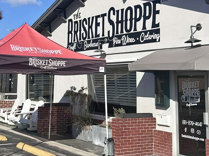 The white facade of The Brisket Shoppe beckons like a BBQ lighthouse, with those Adirondack chairs practically begging you to sit and savor.