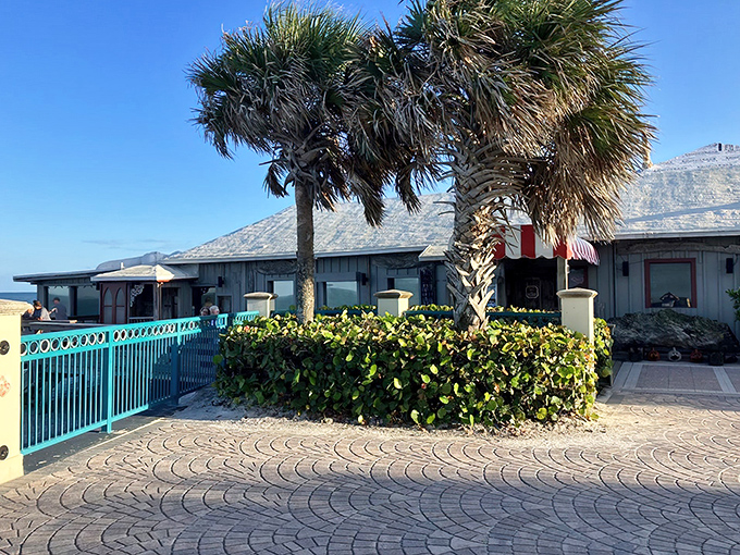 Old Florida charm greets you at Ocean Grill's entrance, where swaying palms and turquoise railings promise seafood paradise awaits just steps from the Atlantic.
