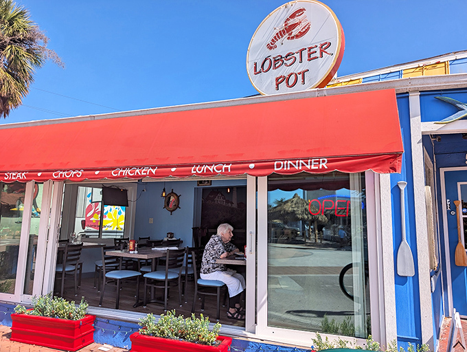 The iconic red awning and circular sign of The Lobster Pot beckon seafood lovers like a lighthouse guiding hungry sailors home.