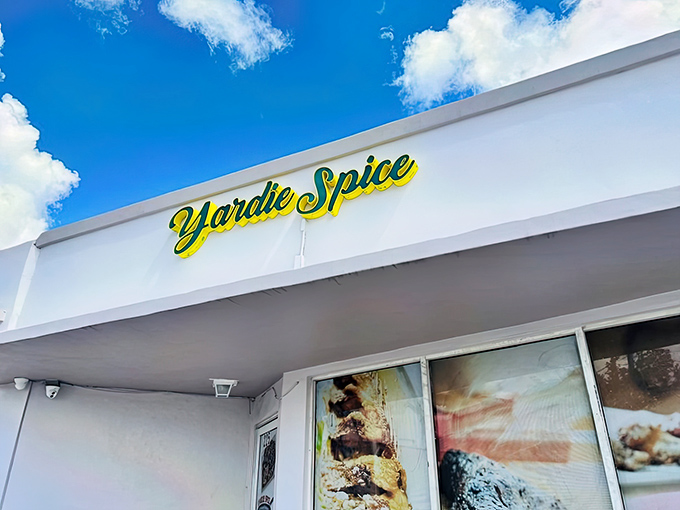 The bright yellow and green sign of Yardie Spice stands out against the Florida sky like a beacon of Caribbean flavor calling you home.