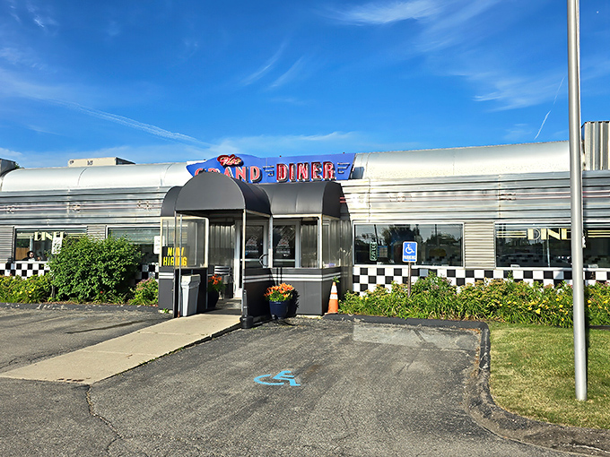 The gleaming silver exterior of The Grand Diner stands like a time machine to the golden age of roadside Americana. That checkered trim promises good things await inside.