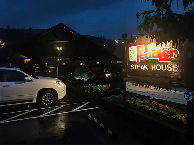 The Peddler's illuminated sign glows like a beacon for hungry travelers. Mountain twilight transforms this rustic steakhouse into a carnivore's North Star.
